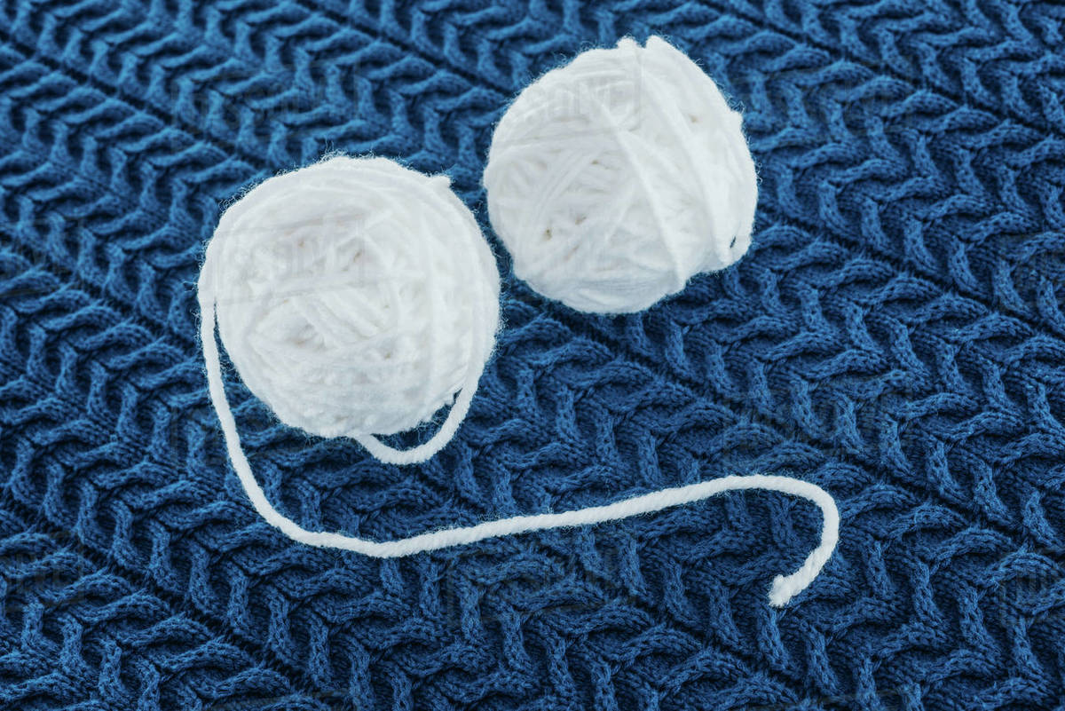 Two knitting yarn balls on blue knit - Royalty-free Stock Photo | Dissolve