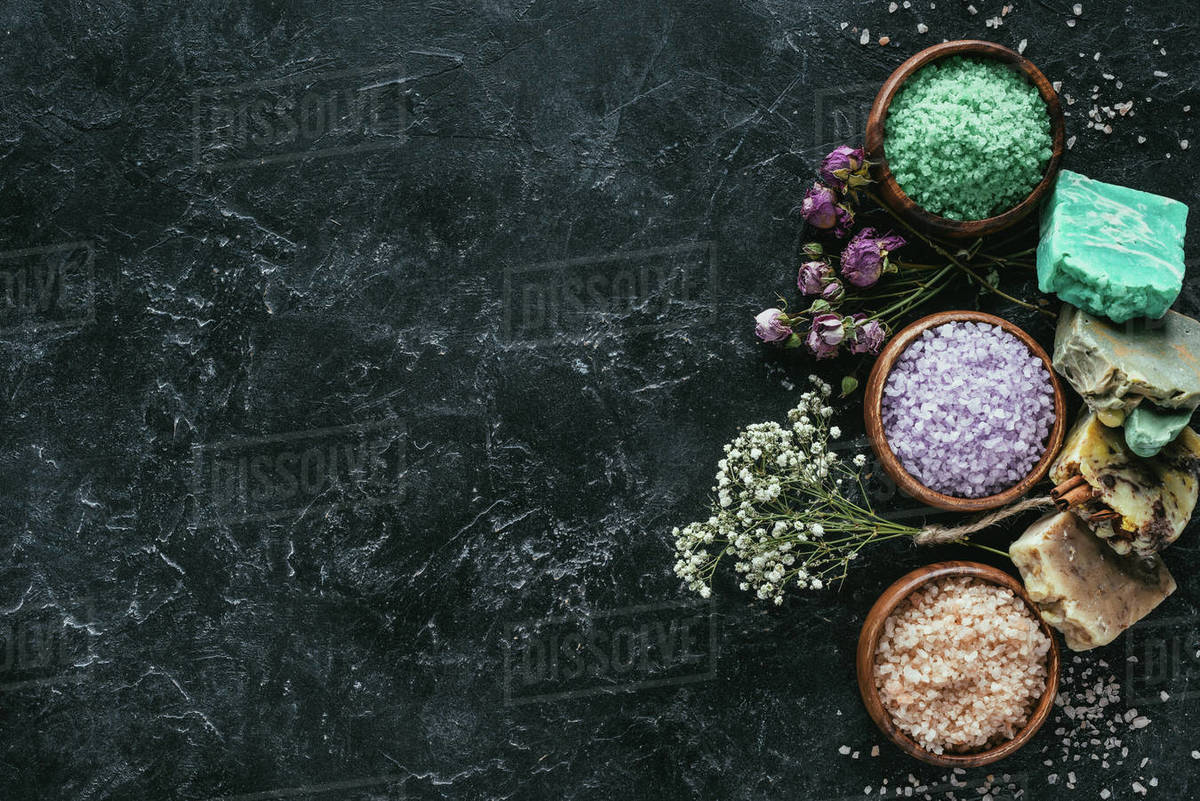 Flat lay with homemade soap, dried flowers and sea salt in wooden bowls ...