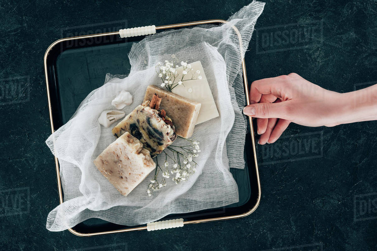Cropped view of hand with natural homemade soap on gauze in tray ...