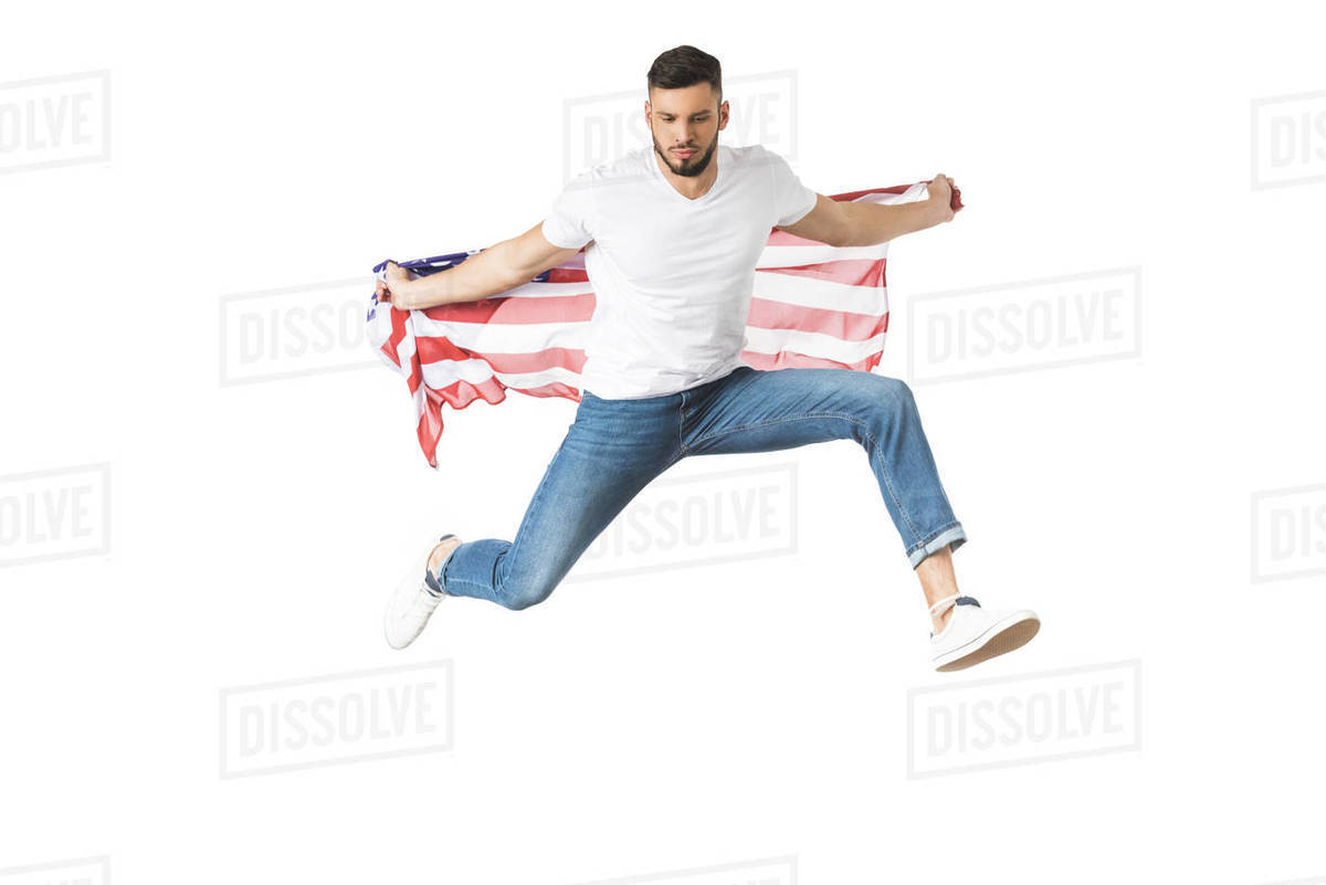 Handsome young man holding american flag and jumping isolated on white ...
