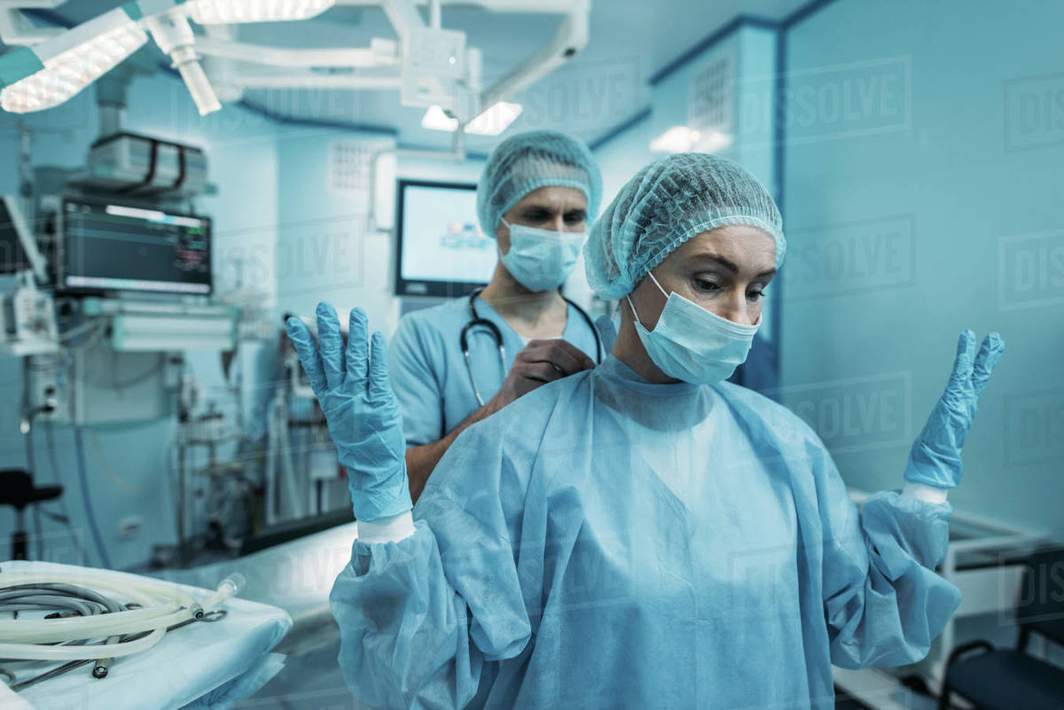 Doctor helping to wear surgical uniform for surgeon - Stock Photo ...