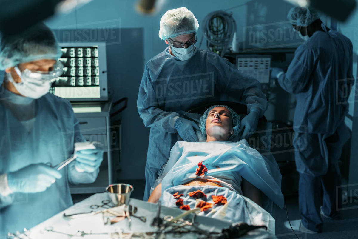 Multicultural surgeons and female patient in operating room - Royalty ...