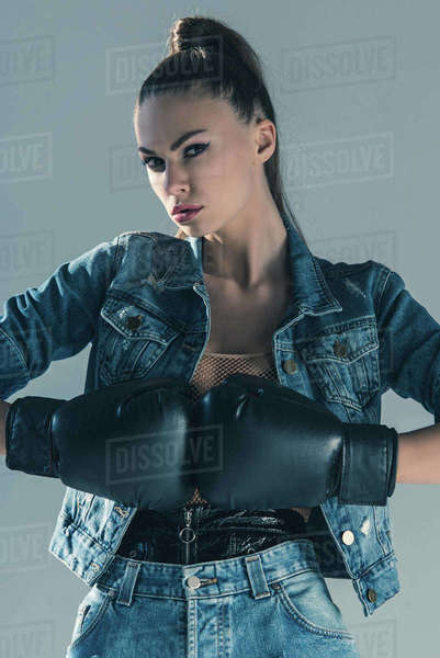 stylish model in denim clothes and boxing gloves, isolated on grey ...