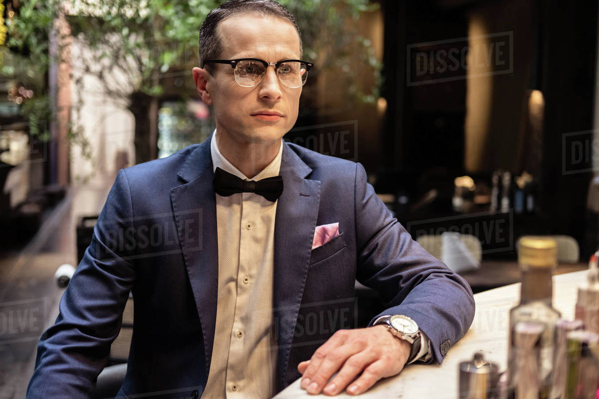 handsome man in stylish suit sitting at bar counter of luxury ...