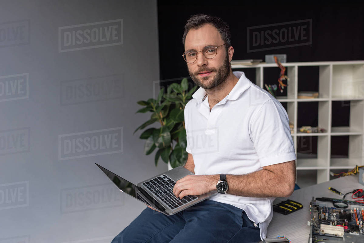 Man sitting on table and using laptop - Stock Photo - Dissolve