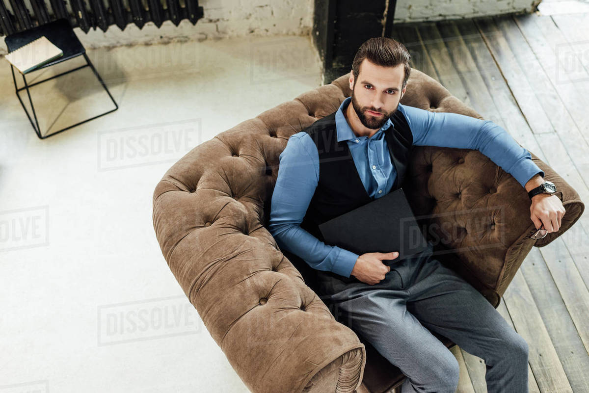 Overhead view of businessman holding notebook and sitting in armchair ...
