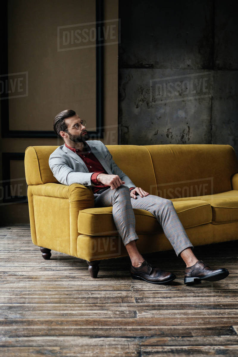 Handsome stylish elegant man sitting on couch in loft interior ...