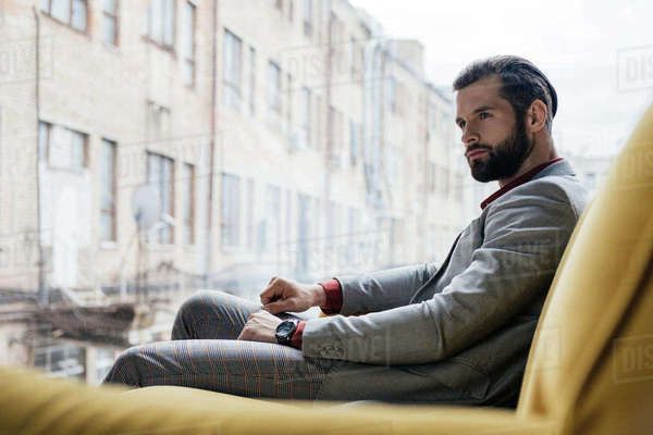 Stylish pensive man sitting on yellow sofa at window - Stock Photo ...