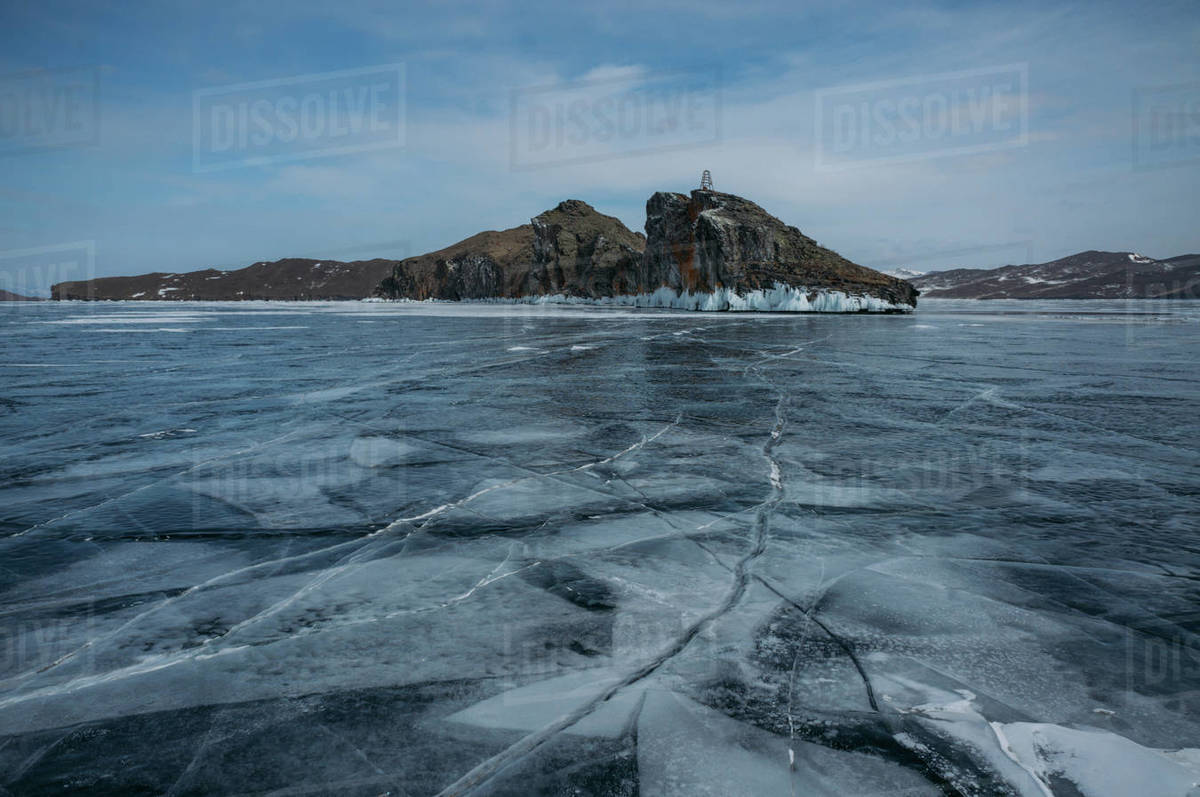 View of ice covered water surface of lake and rock formations on ...