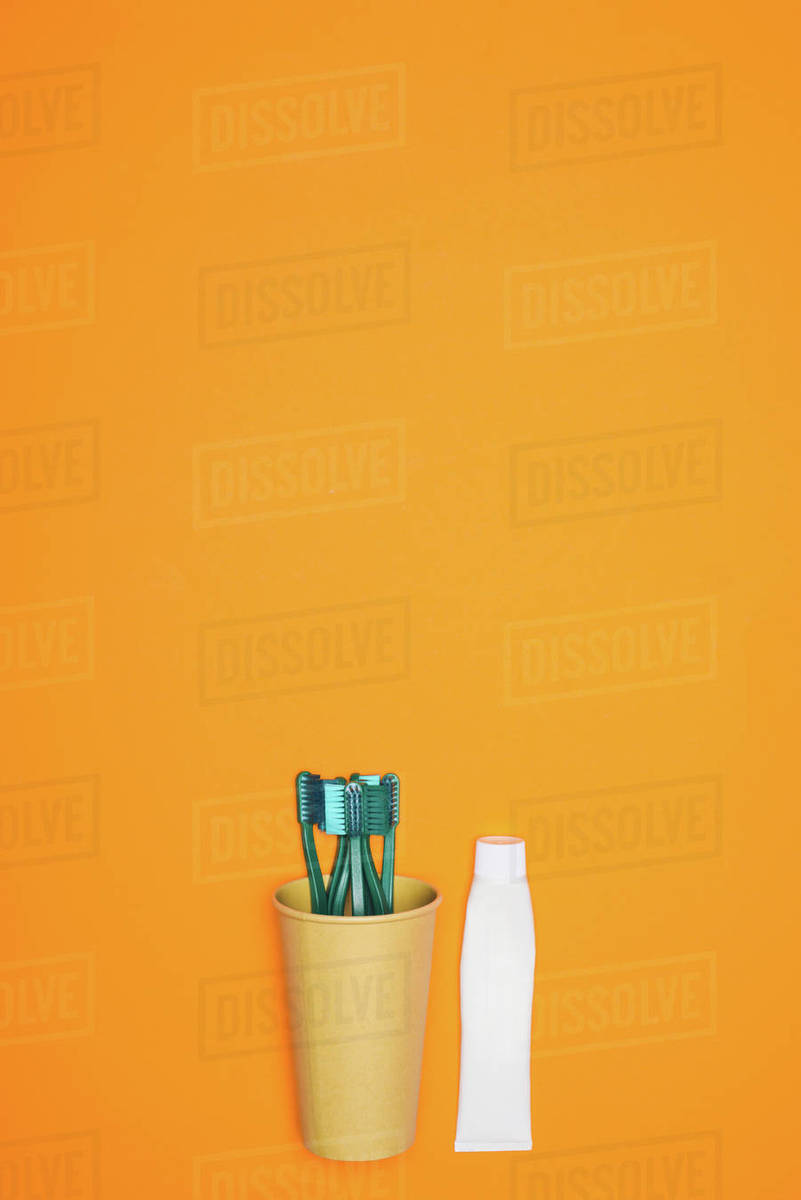 Top view of toothbrushes in paper cup and tube of toothpaste, isolated ...