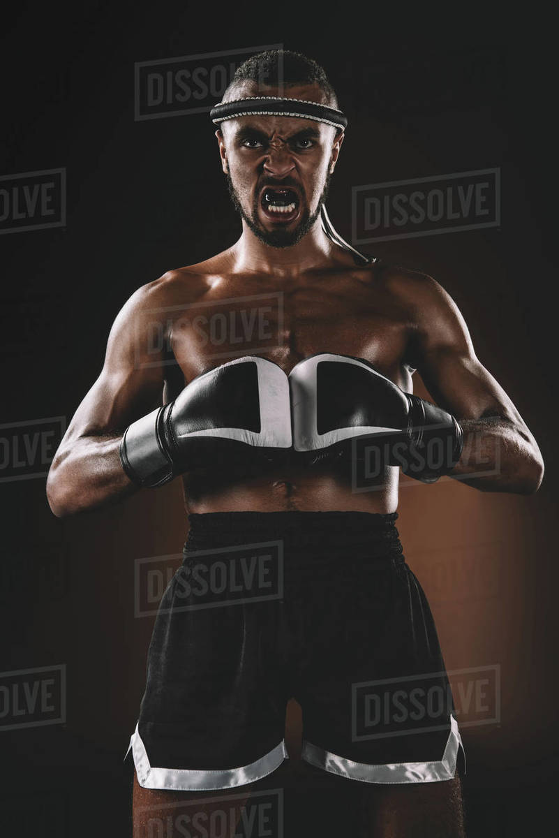 Aggressive muay thai fighter with boxing gloves looking at camera ...