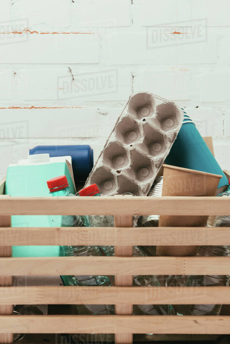 Close up view of various types of trash in wooden box with white brick ...