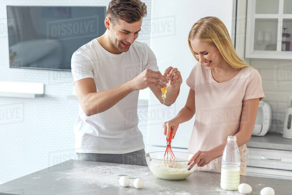 Beautiful young couple cooking breakfast together on kitchen on weekend ...