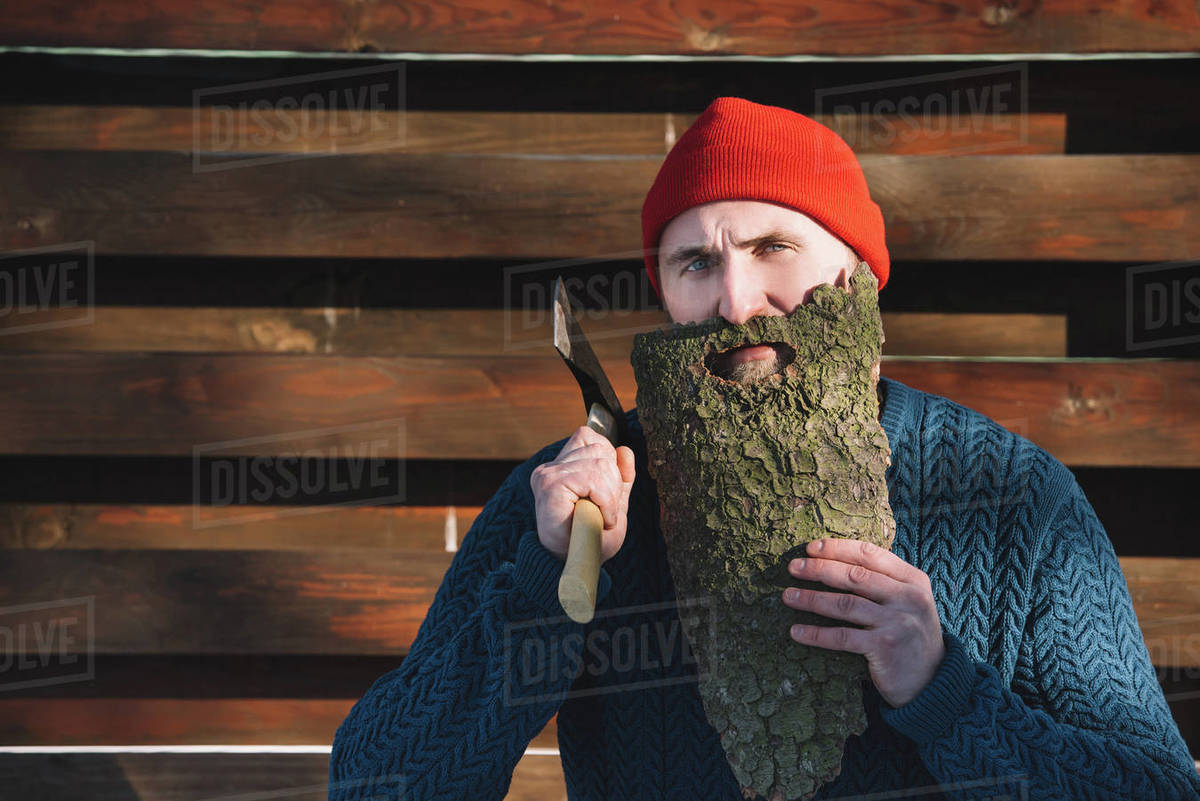 Portrait of man with beard made of wood bark and axe in hand outdoors ...