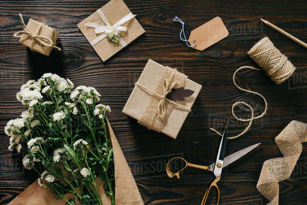 Flat lay with wrapped presents, bouquet of flowers, rope and scissors ...