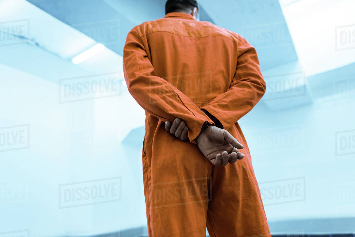 Bottom view of prisoner in orange uniform standing in prison cell ...