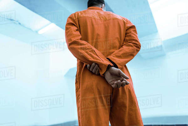 Bottom view of prisoner in orange uniform standing in prison cell ...
