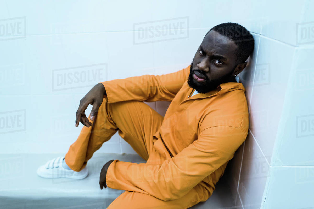 African American prisoner sitting on bench and looking at camera ...