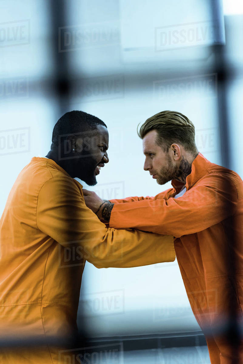 Side view of multicultural prisoners threatening each other and holding ...