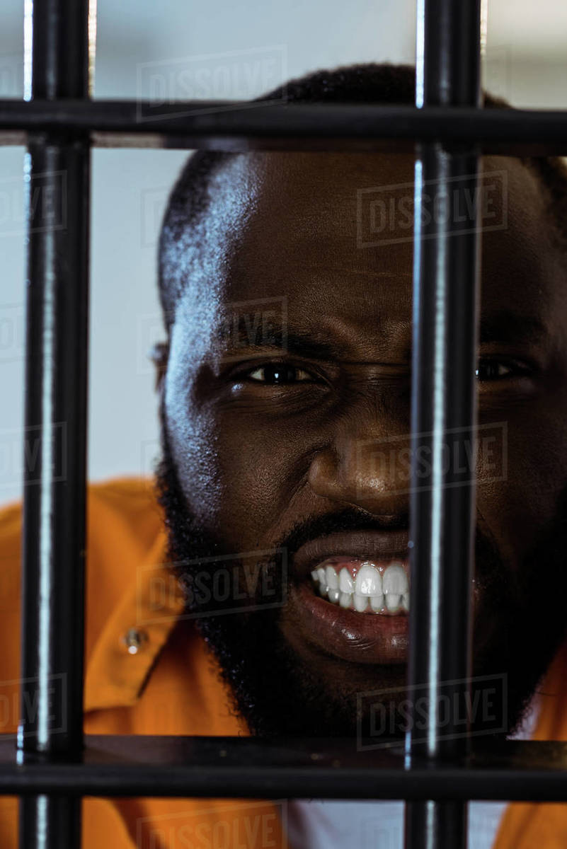 Aggressive African American prisoner behind prison bars - Royalty-free ...