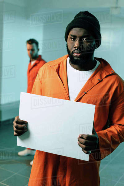 african american prisoner holding blank placard and looking at camera ...