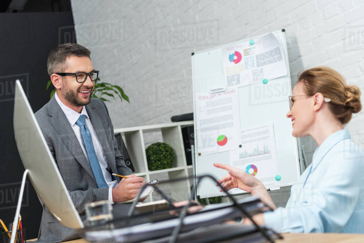 Businesspeople having conversation at workplace in office - Royalty ...