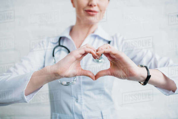 Cropped shot of female doctor showing heart sign with hands - Royalty ...