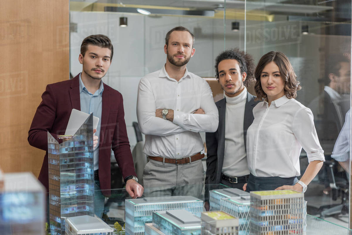 Group of architects standing next to building models at office ...