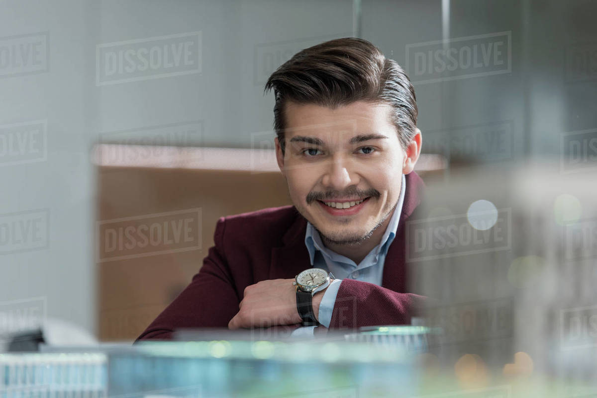 Handsome smiling architect looking at camera at office behind building ...