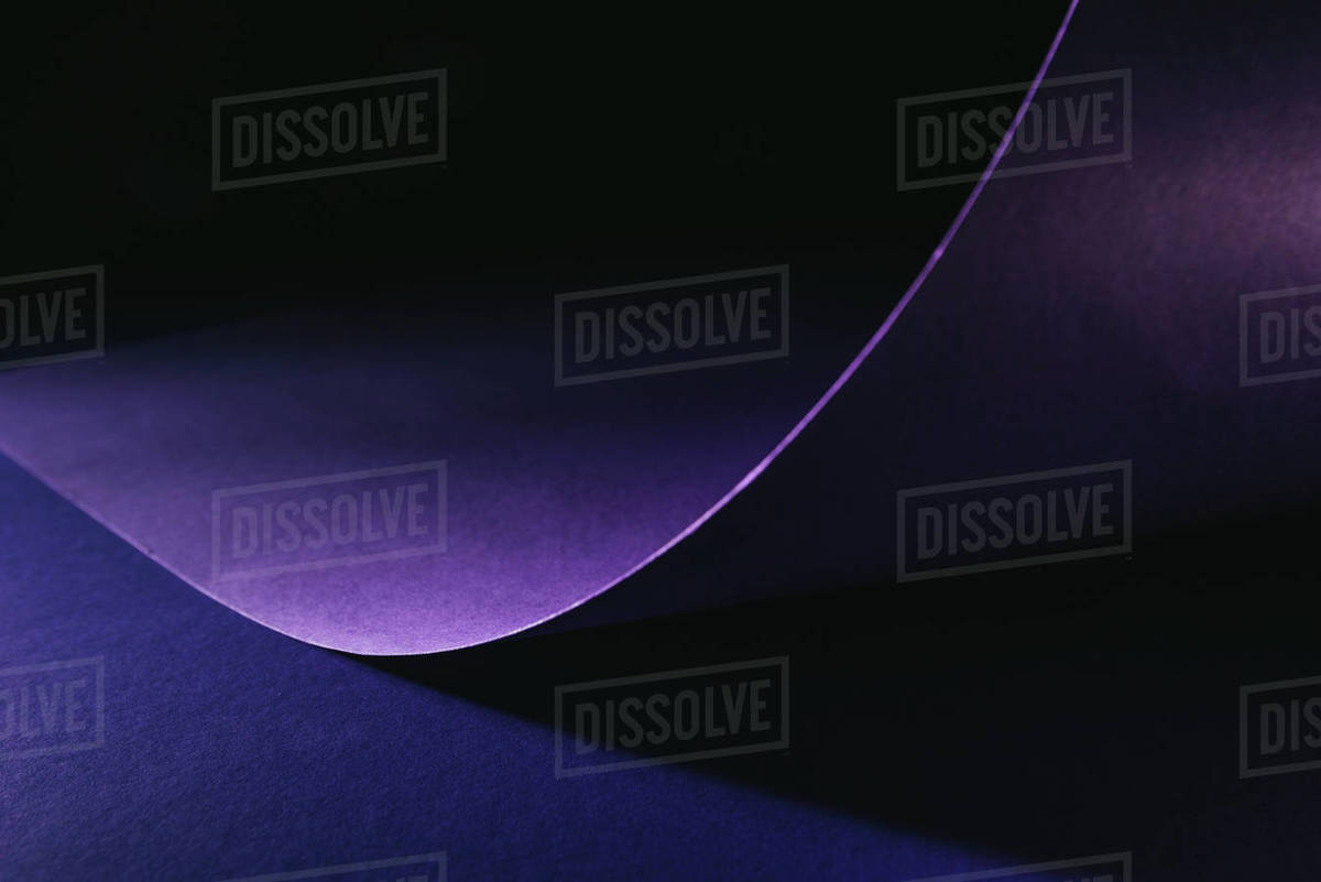 Warping purple paper on purple surface on black - Stock Photo - Dissolve