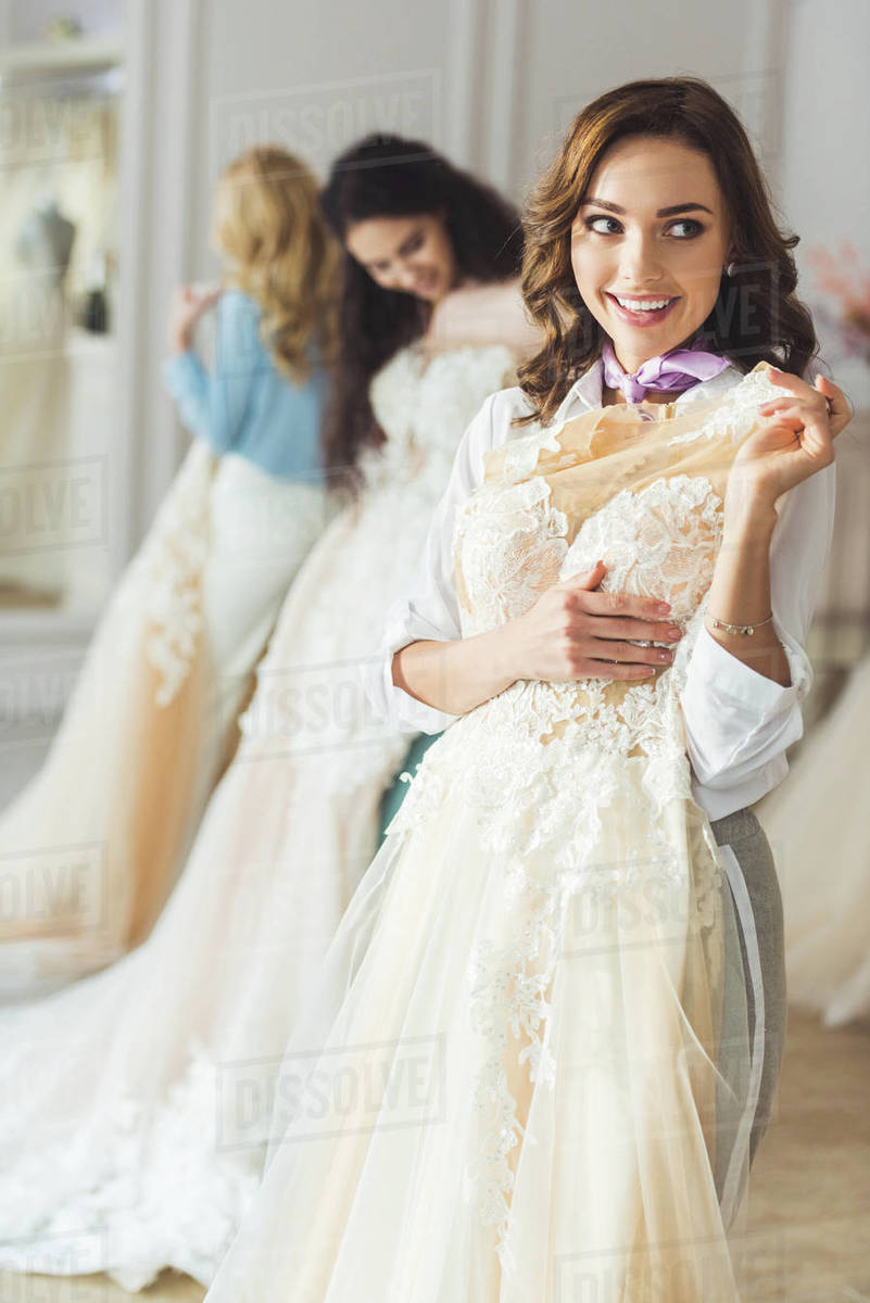 Smiling women with wedding dresses in wedding salon - Royalty-free ...