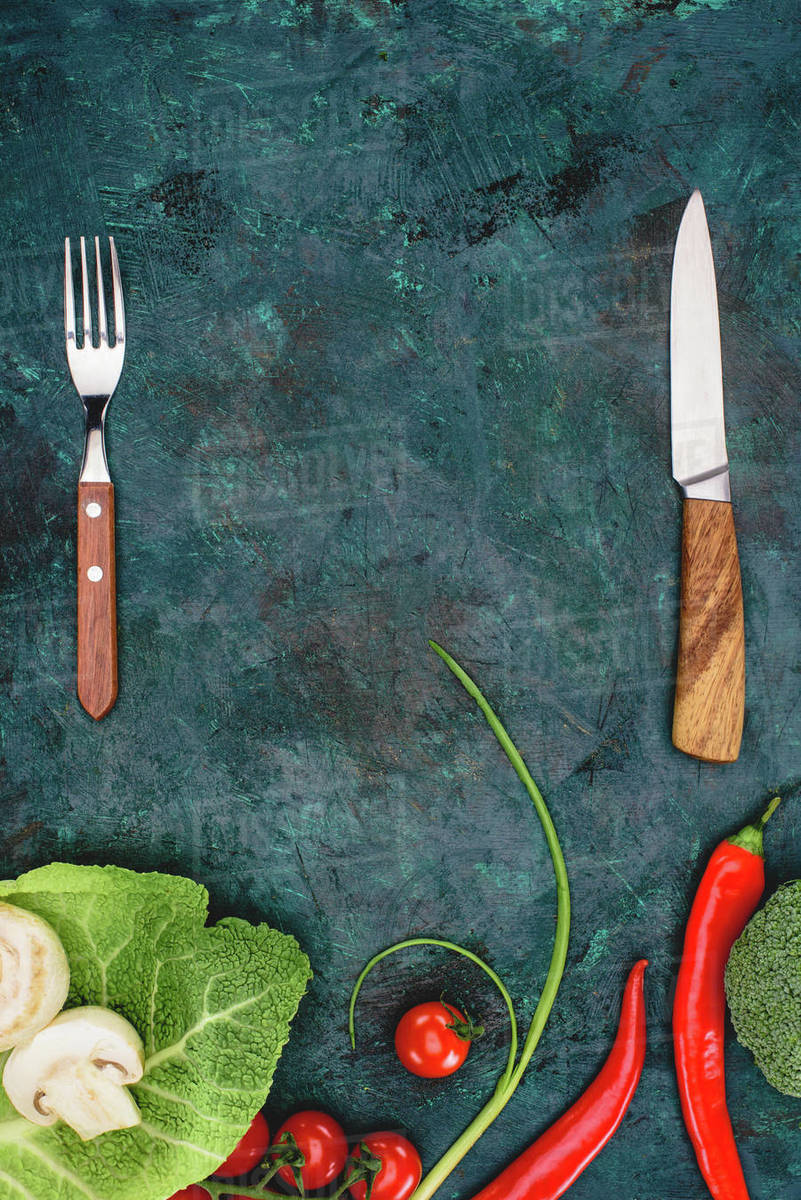 Top view of fork with knife and fresh healthy vegetables on black ...