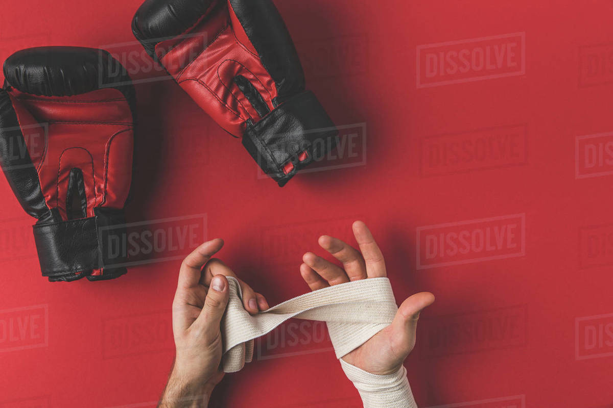 cropped shot of boxer covering up hands in elastic bandage before fight ...