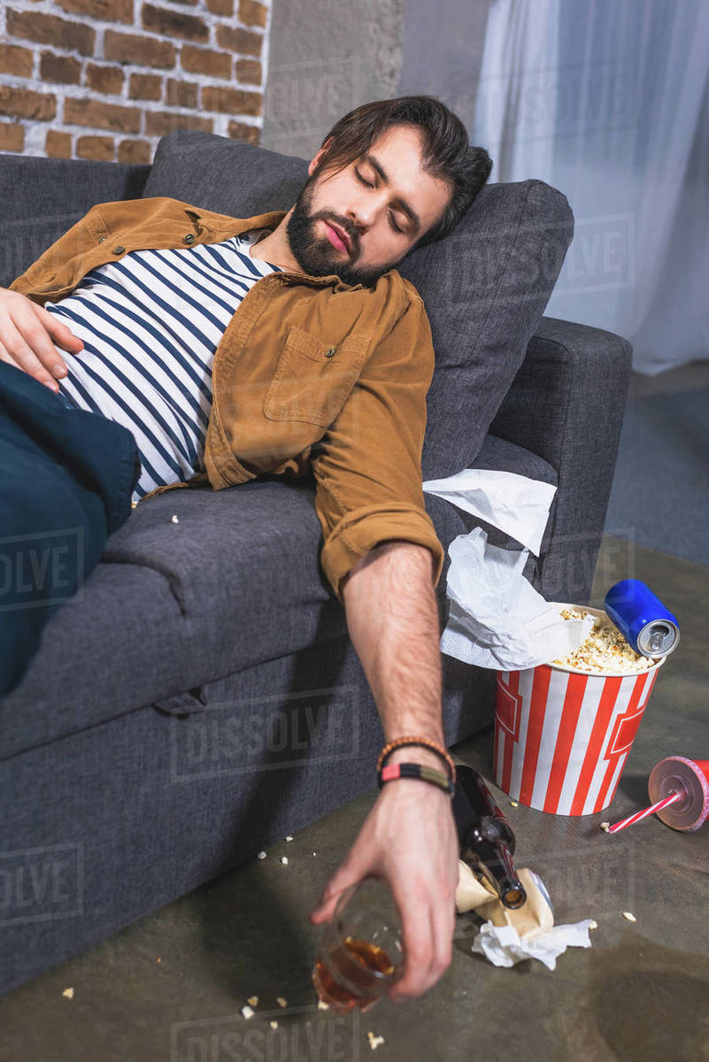 Loner sleeping on sofa with glass of whiskey at living room - Royalty ...