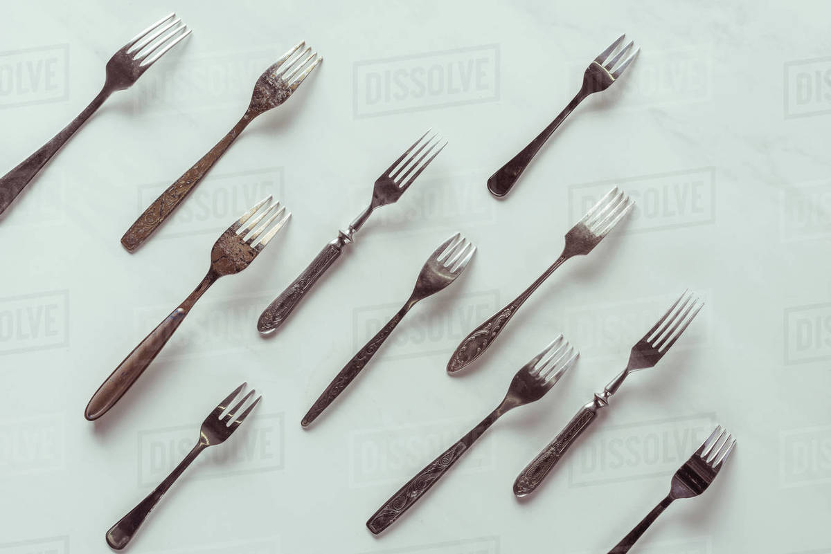 Old metal forks in rows on white background - Stock Photo - Dissolve