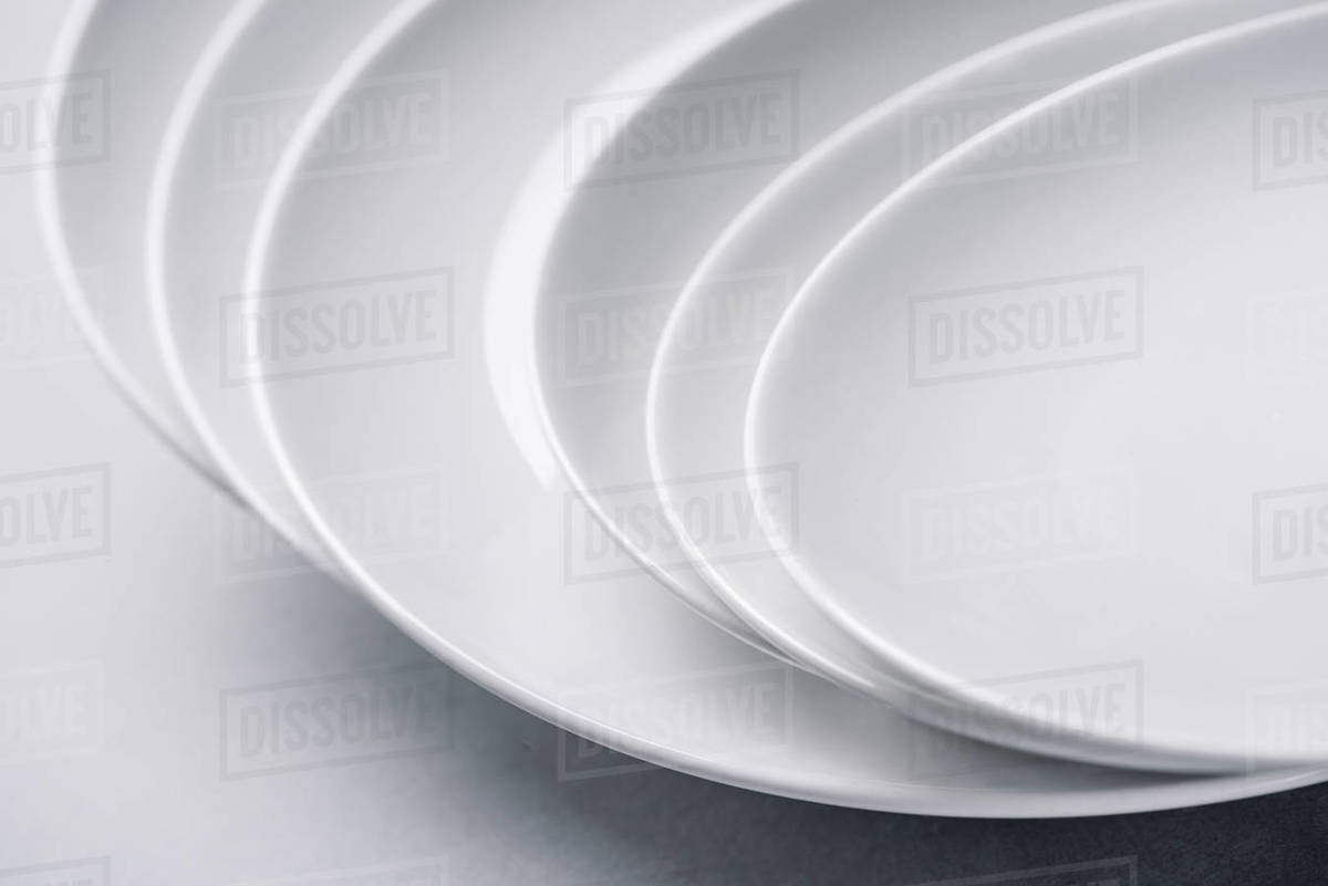 White ceramic plates stacked on white background - Stock Photo - Dissolve
