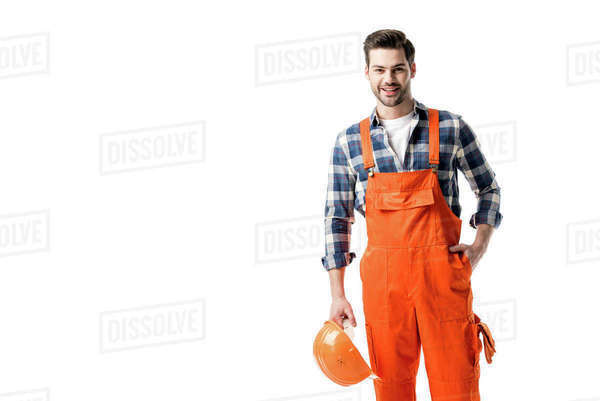 Smiling handyman in orange overall holding hard hat isolated on white ...