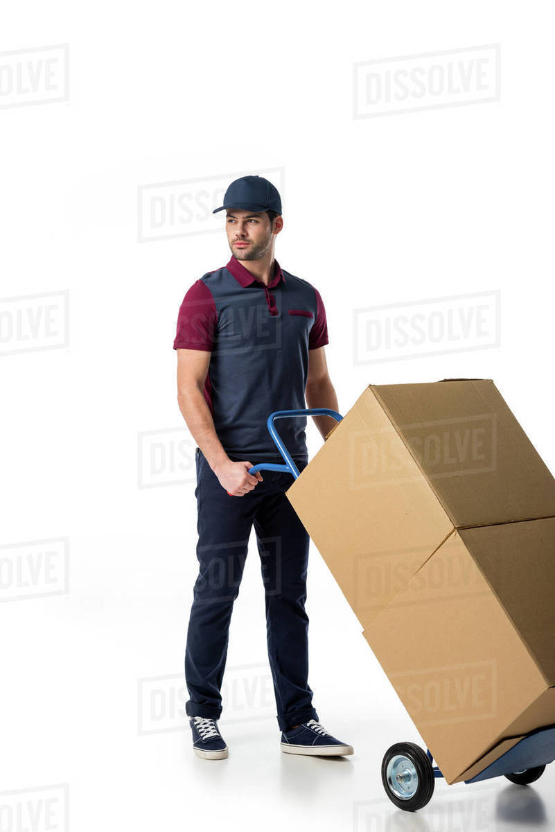 Delivery man in uniform pushing hand truck with cardboard boxes ...