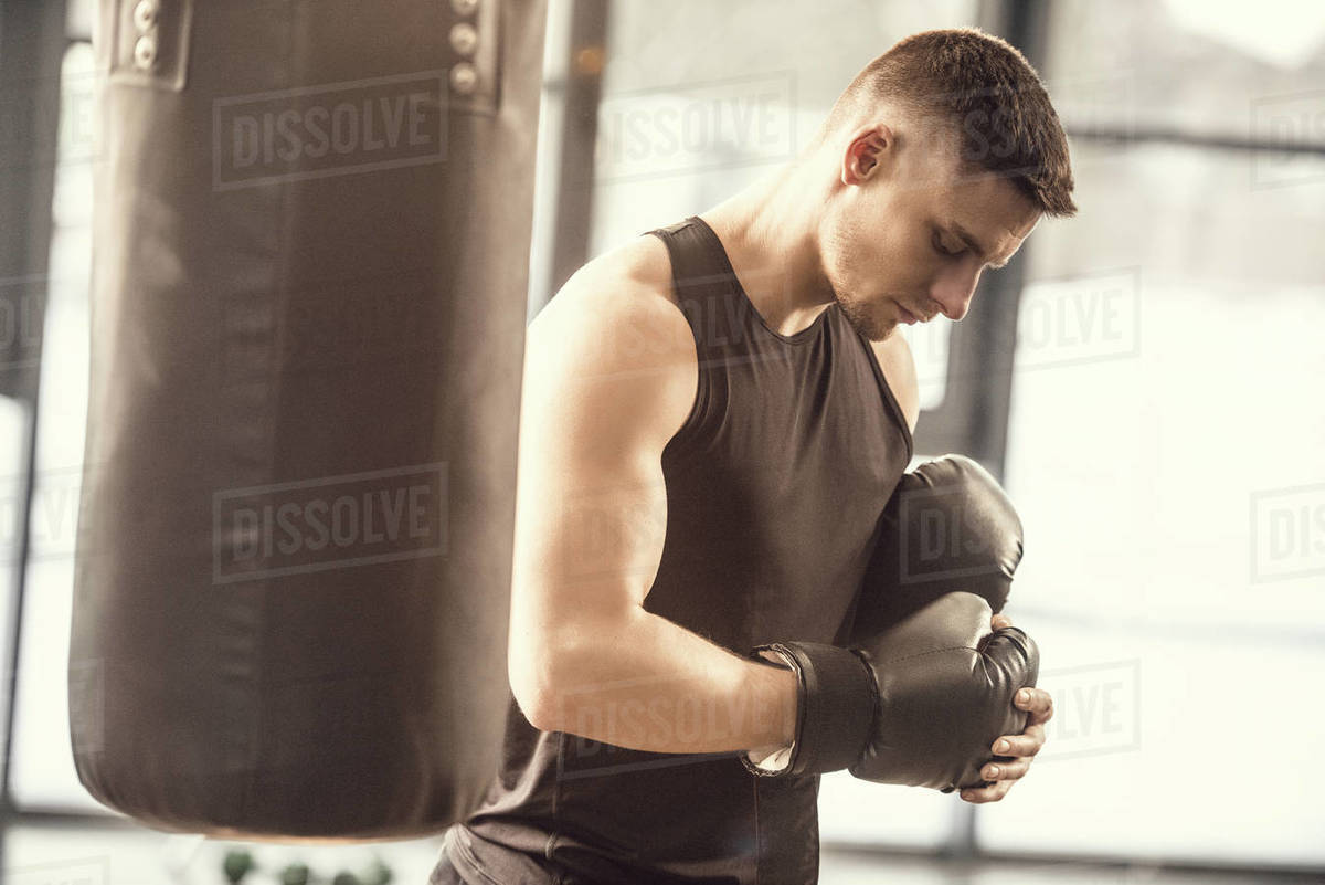Side view of muscular sportsman wearing boxing gloves in gym - Stock ...