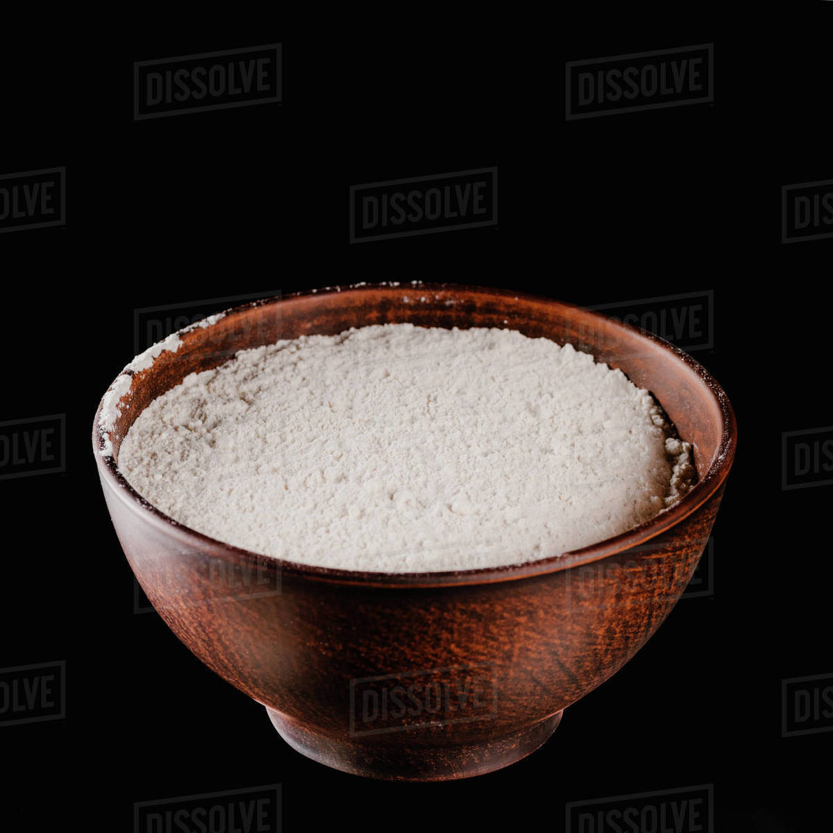 Brown bowl with flour for dough isolated on black - Stock Photo - Dissolve