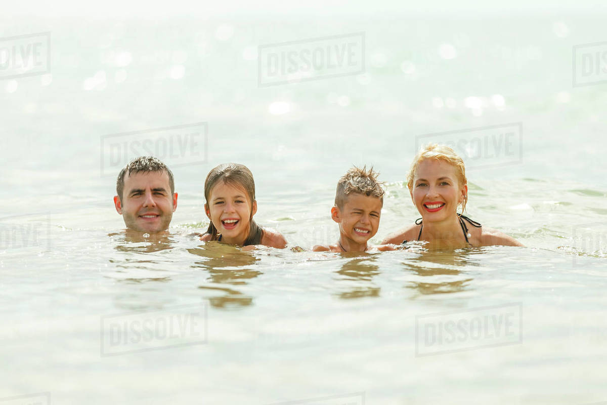 Beautiful happy family swimming in sea together - Stock Photo - Dissolve