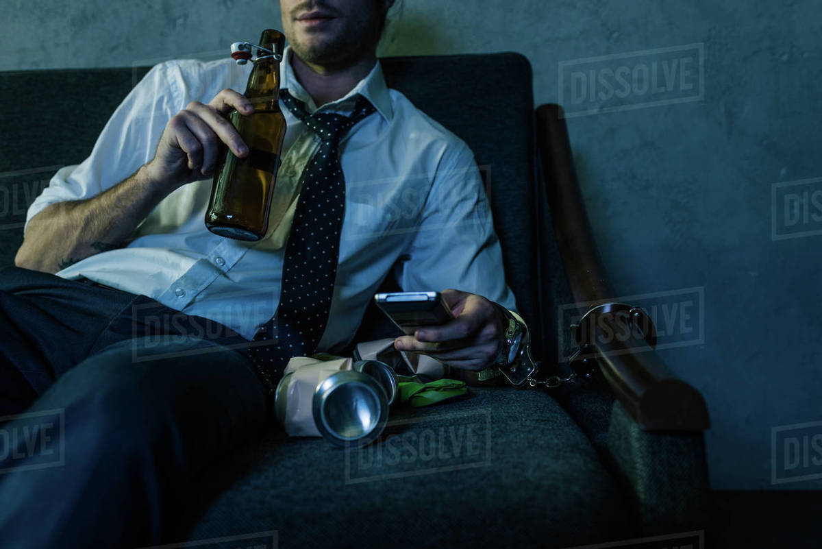 Cropped shot of alcohol addicted man in white shirt watching tv and ...