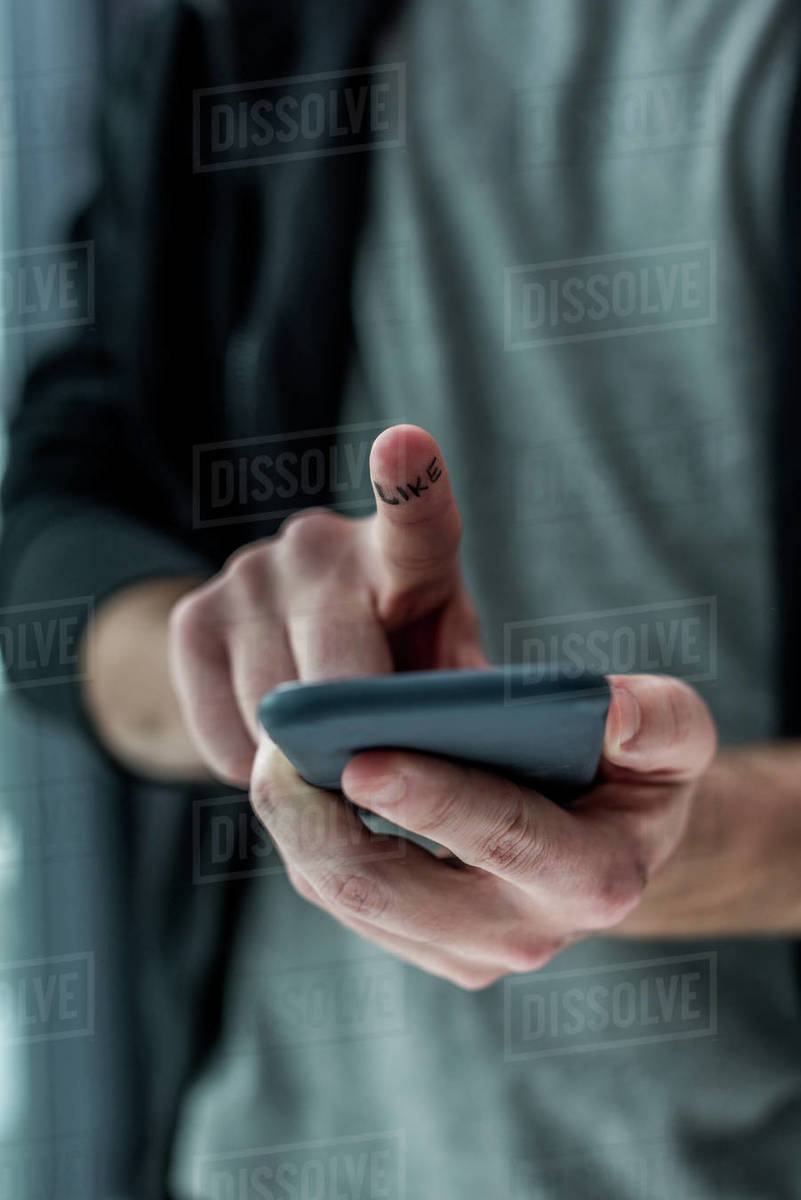 Cropped shot of man touching smartphone screen with like word on finger ...