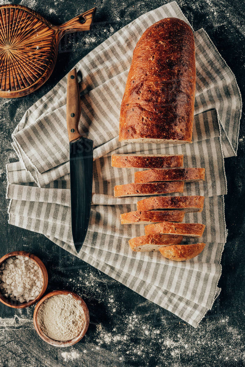 Flat lay with pieces of bread on linen and bowls with flour near by on ...
