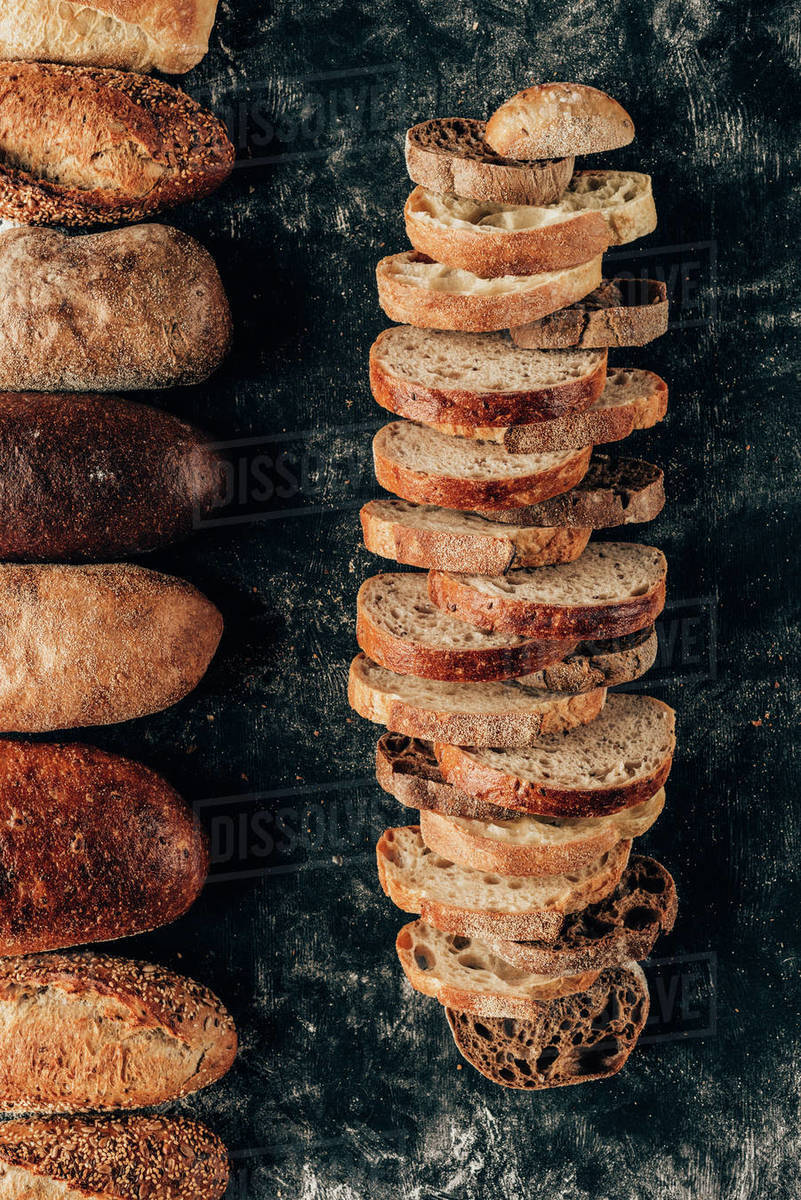 Top view of arranged loafs and pieces of bread on dark tabletop - Stock ...