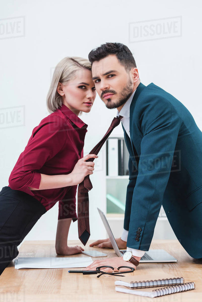 sensual young business colleagues flirting and looking at camera in ...