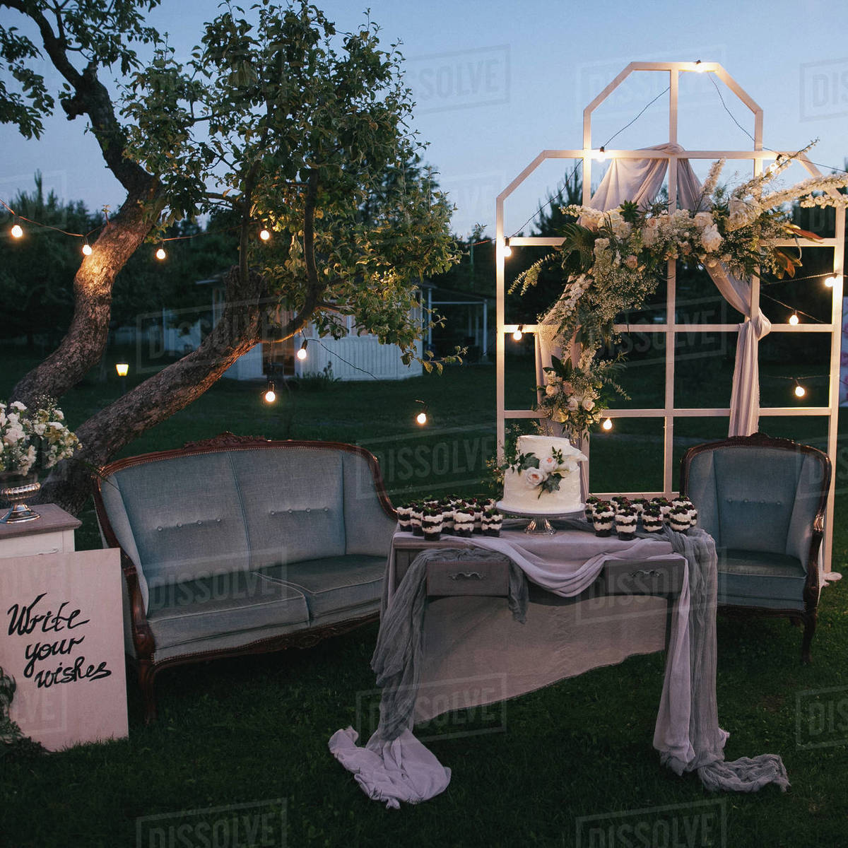 beautiful decorative illuminated wedding arch and cake with desserts on ...