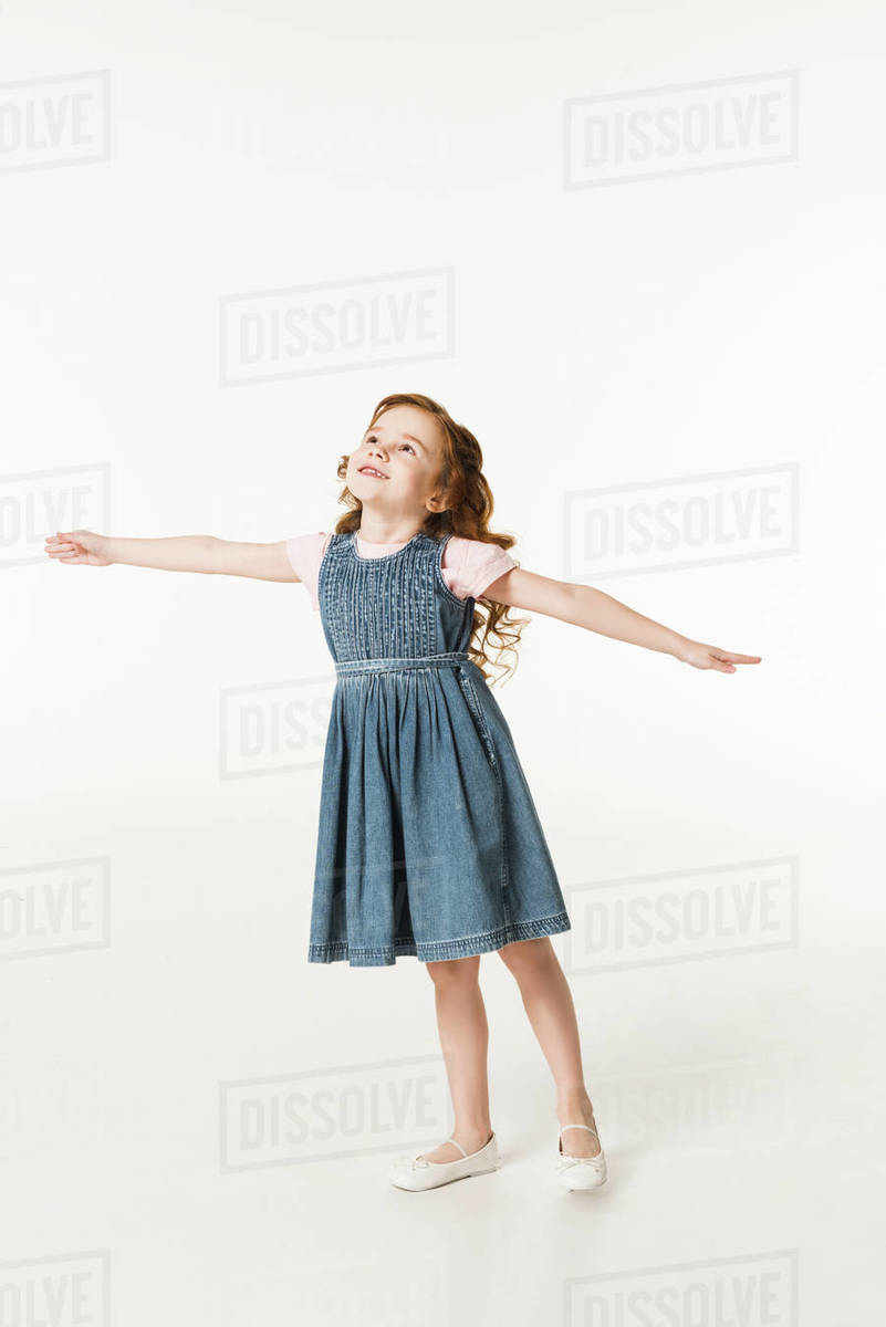 Little stylish kid in dress standing with wide arms isolated on white ...