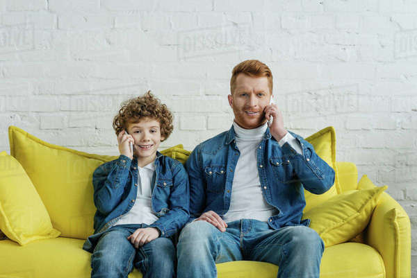 Father and son talking on smartphones looking at camera - Royalty-free ...