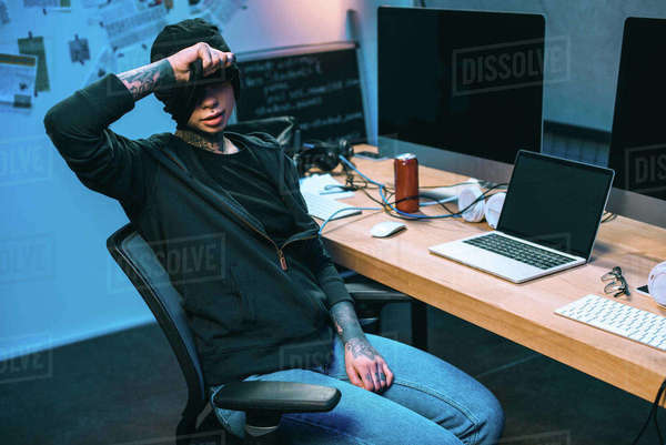 Young female hacker at workplace taking off mask - Royalty-free Stock ...